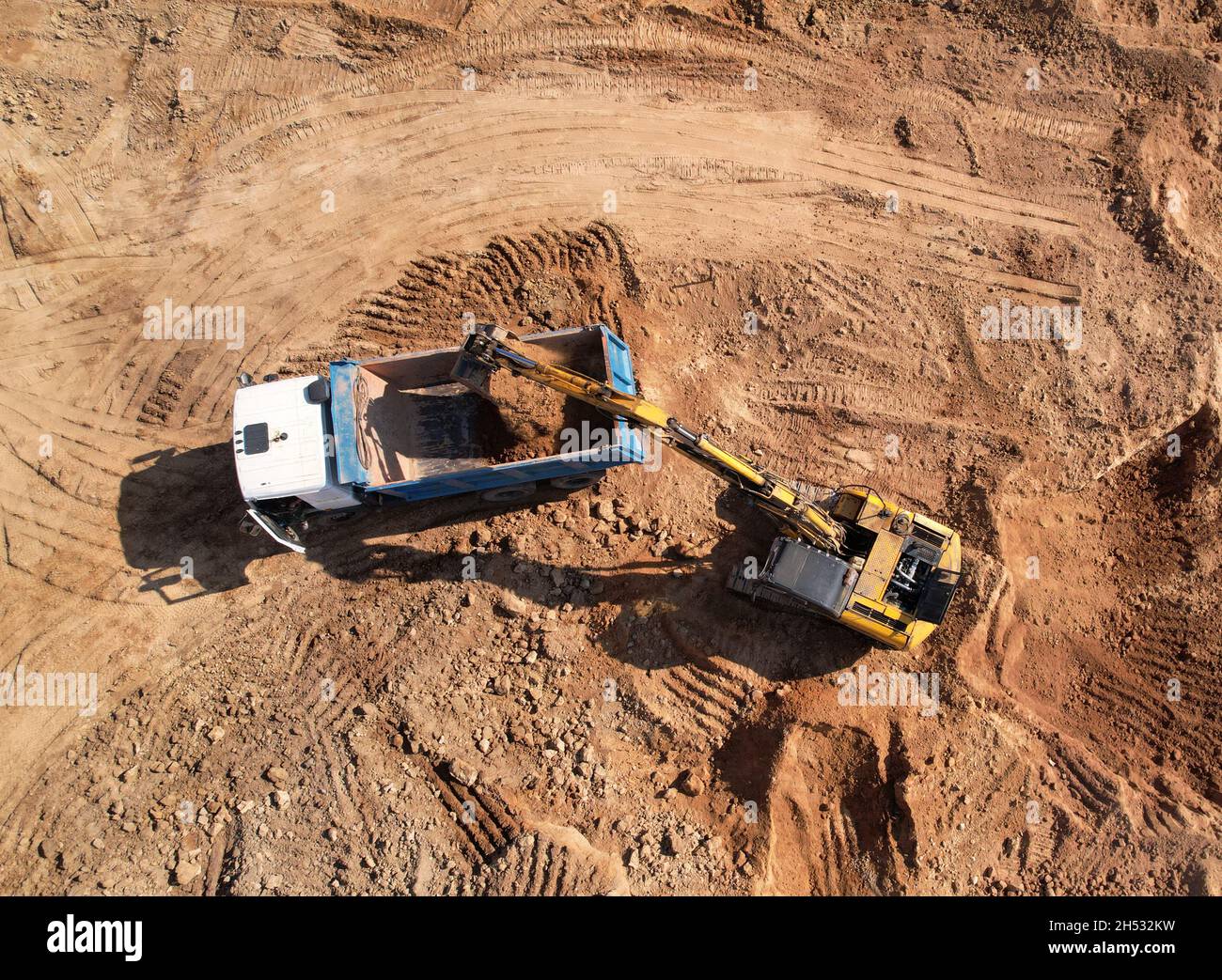 Excavator load the sand into dump truck. Aerial view of an backhoe on ...