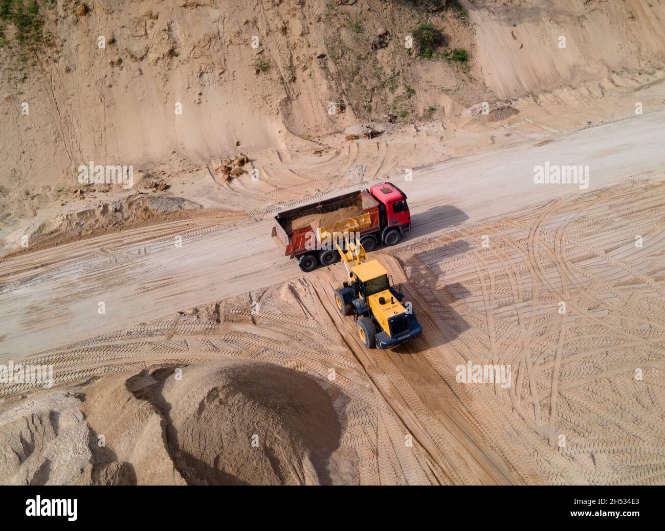 Wheel loader loading sand into dump truck at the open pit mine. Mining ...