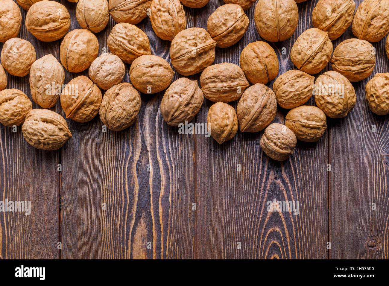 many walnuts with shells randomly scattered on brown wooden surface ...
