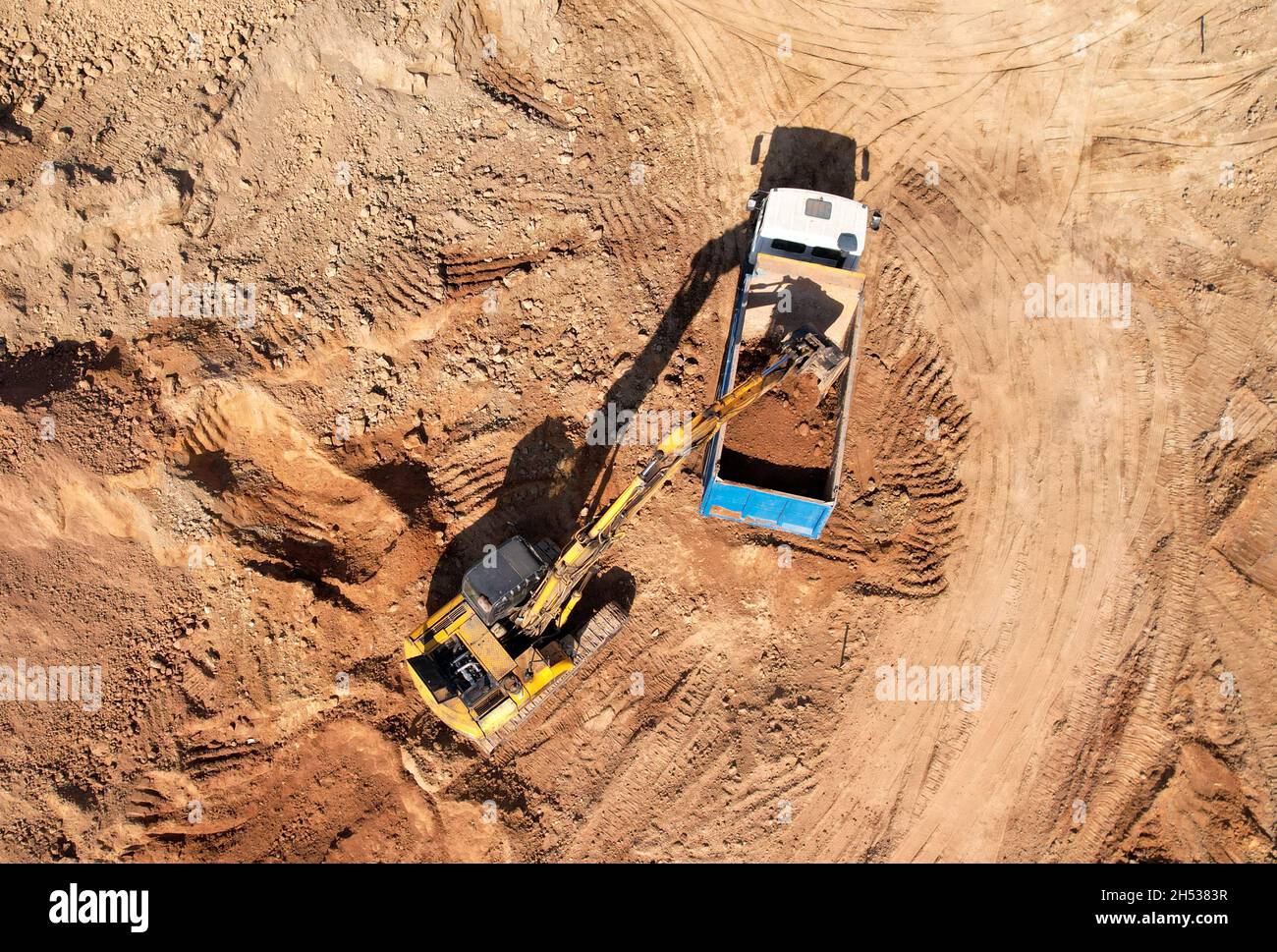 Excavator load the sand into dump truck. Aerial view of an backhoe on ...