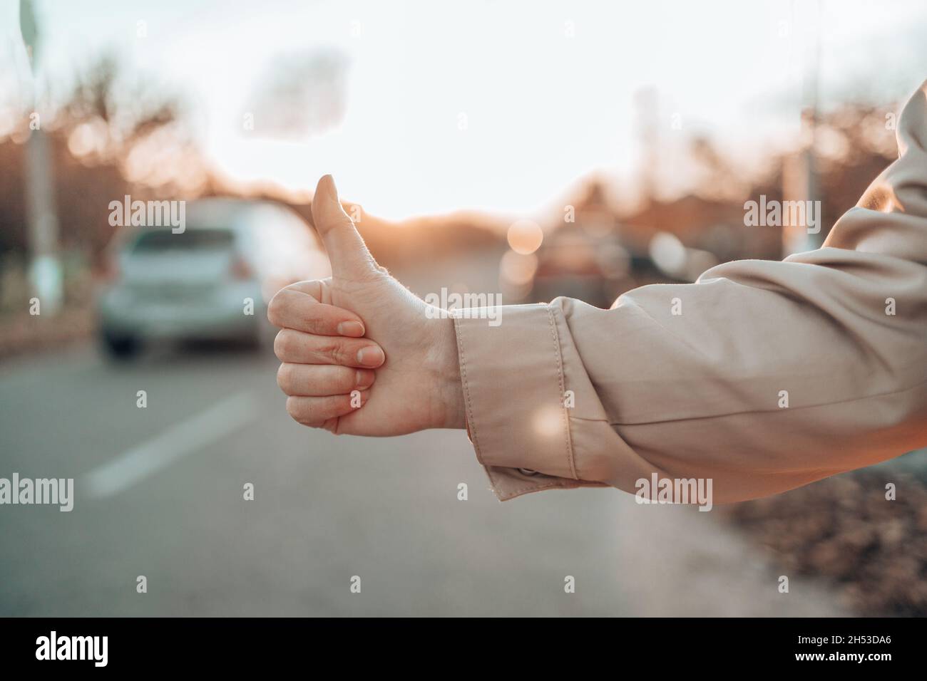 Female hand and hitchhiking sign on road, traveling by autostop in the ...