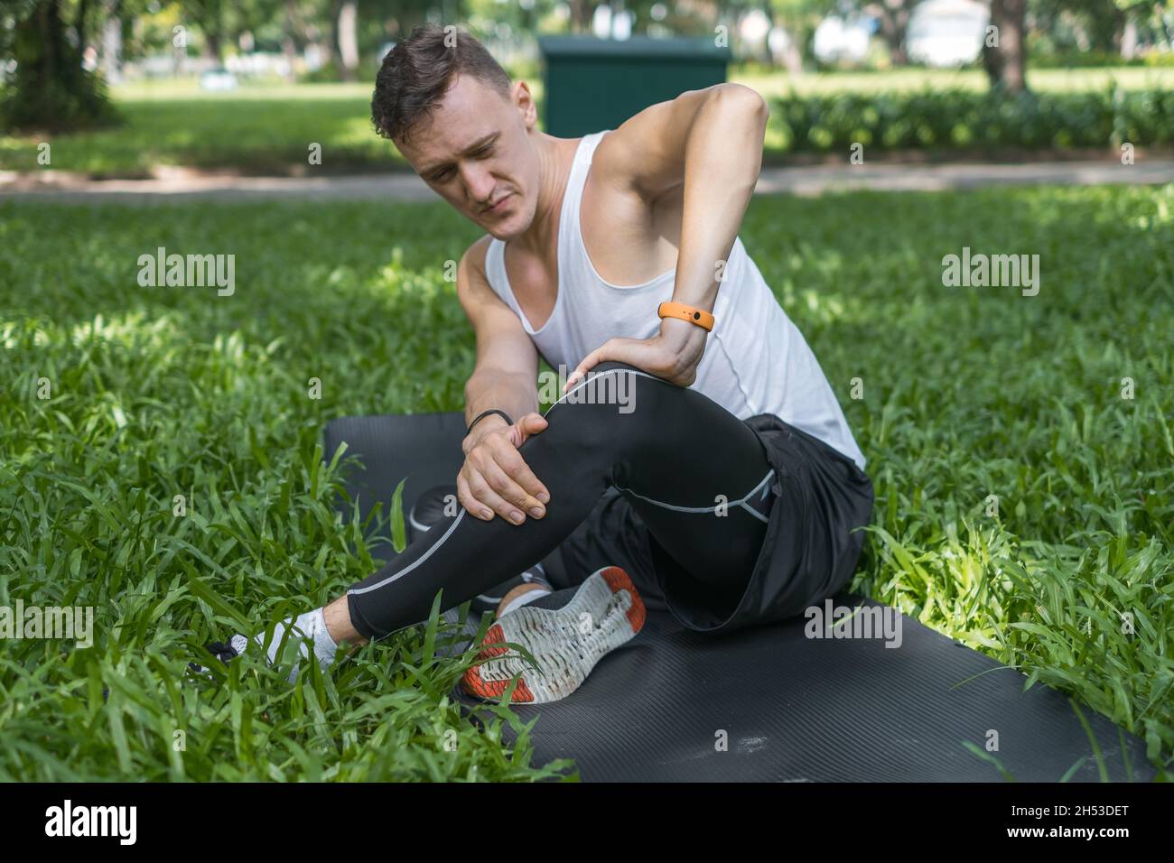 Portrait of man touching his leg with his hand. Man injured his knee ...