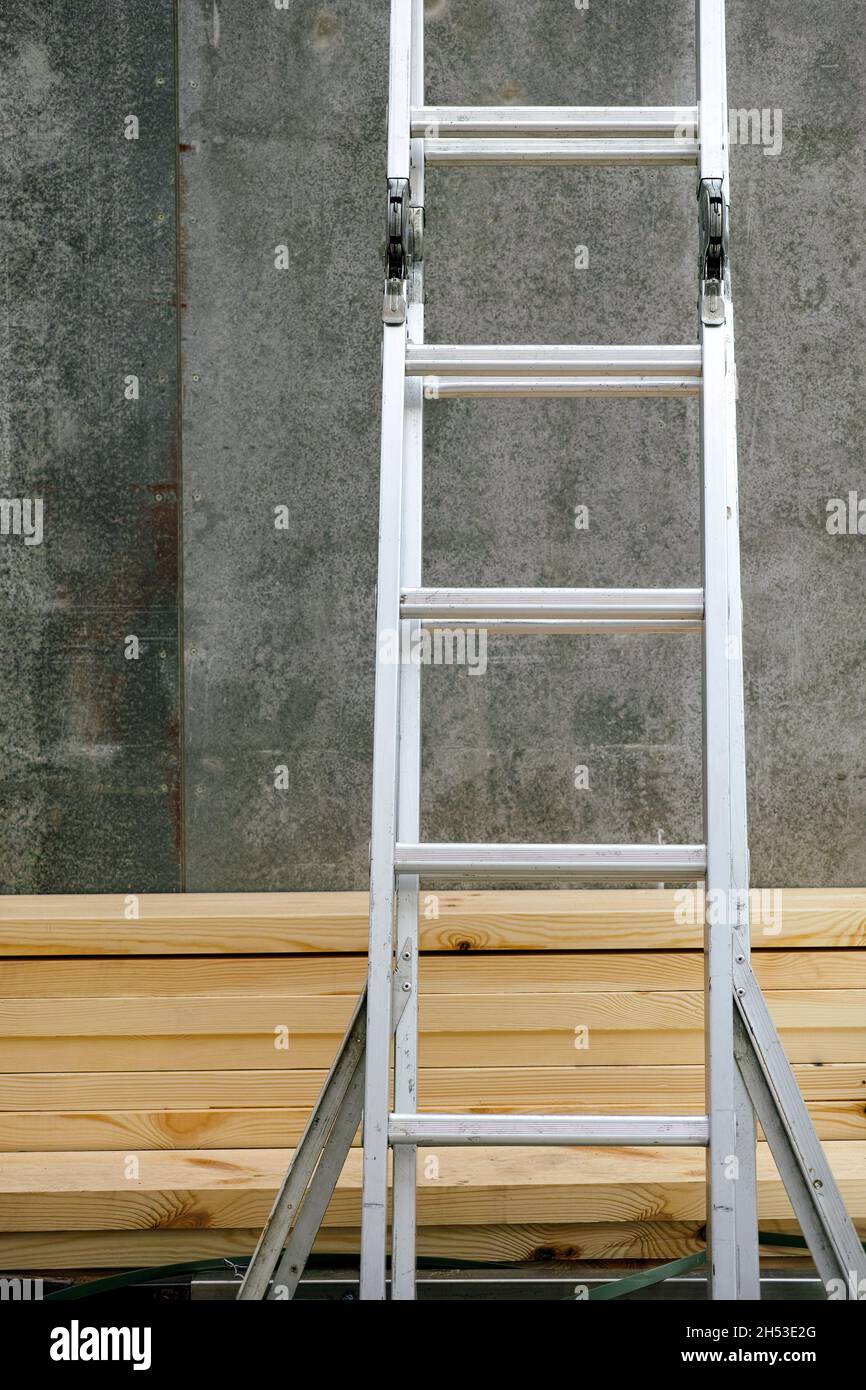 An aluminium multipurpose hinged ladder standing near a wall with ...