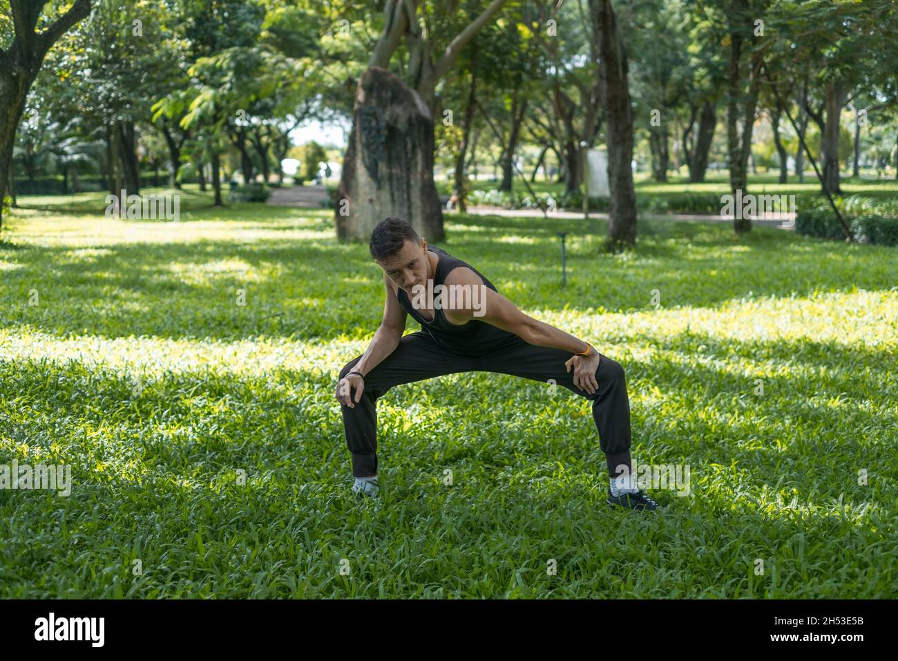 Sporty active young man in black sportswear doing sport exercises in ...