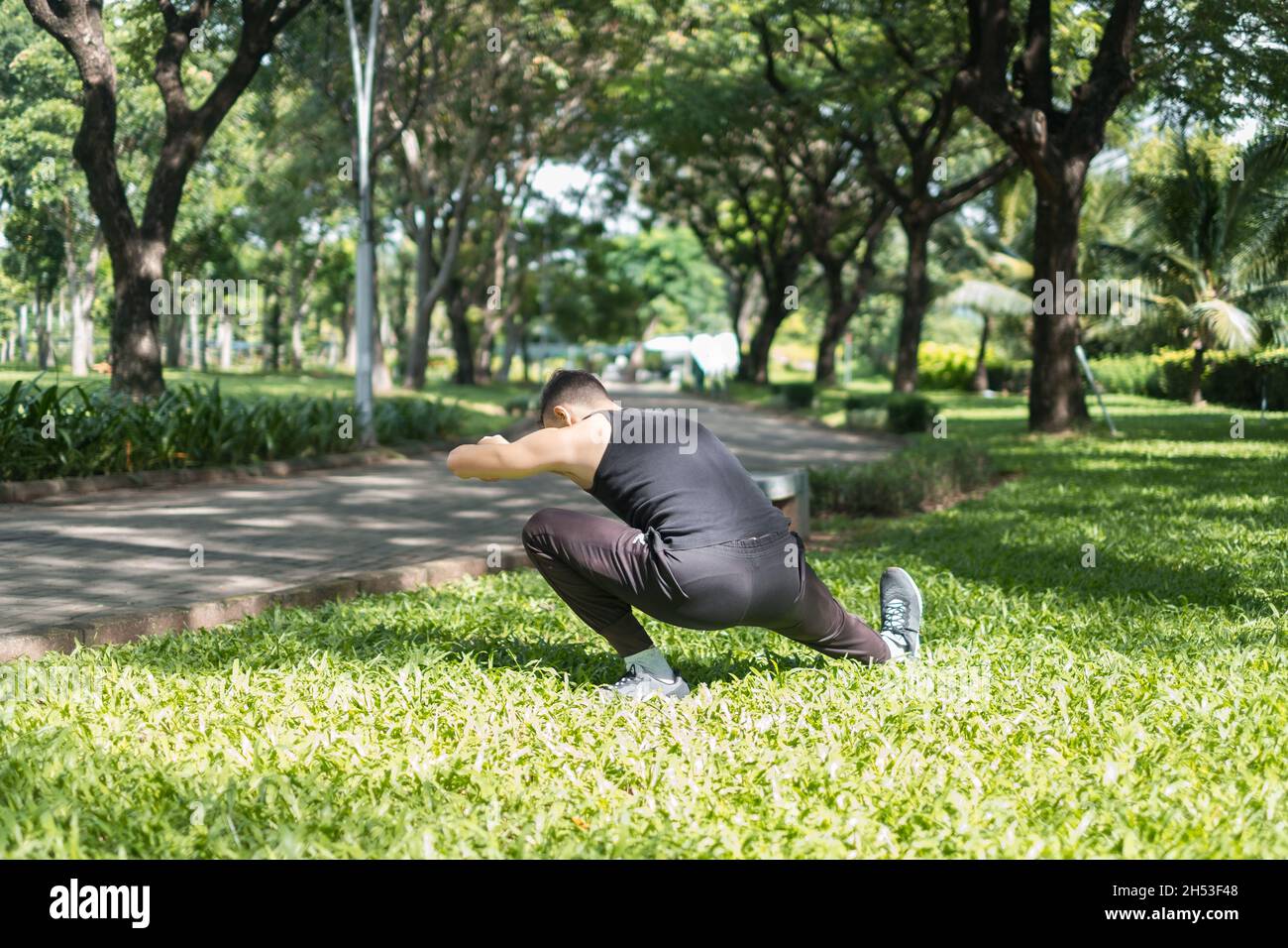 Sporty fit active young man in black sportswear doing sport exercises ...