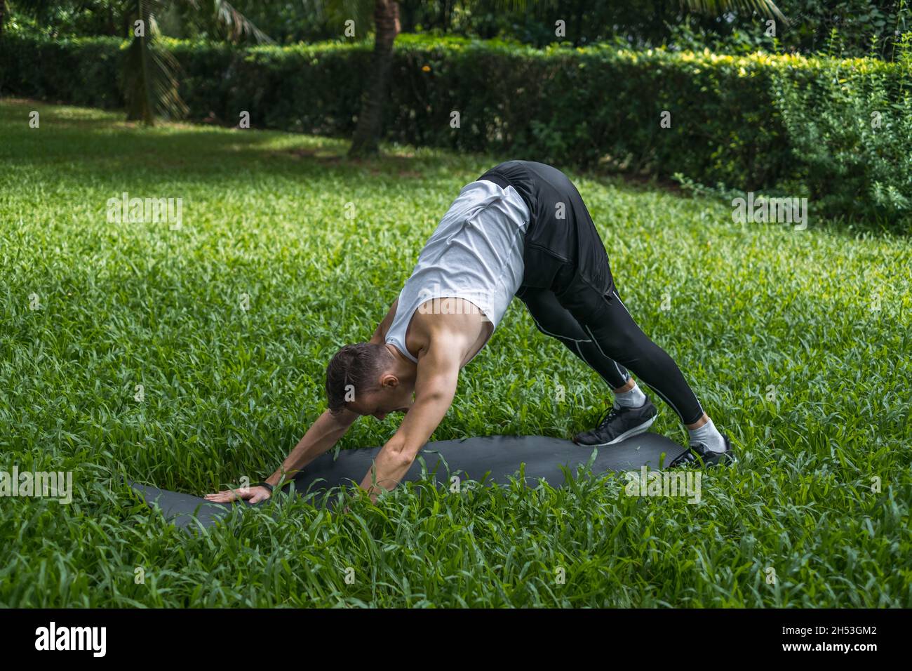 Sporty active young man in sportswear doing sport exercises in the park ...