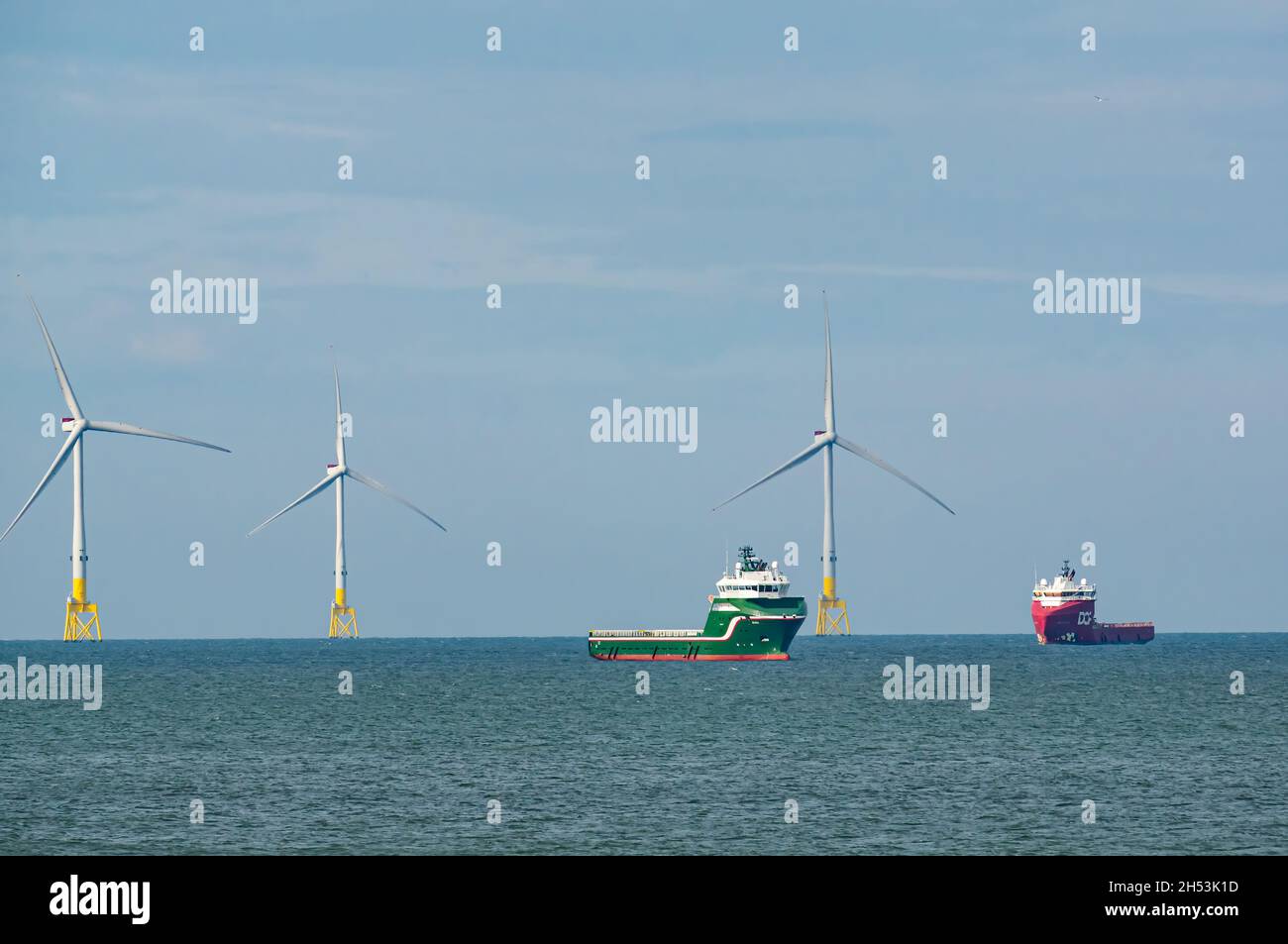 Offshore supply ships anchored by wind turbines in offshore wind farm ...
