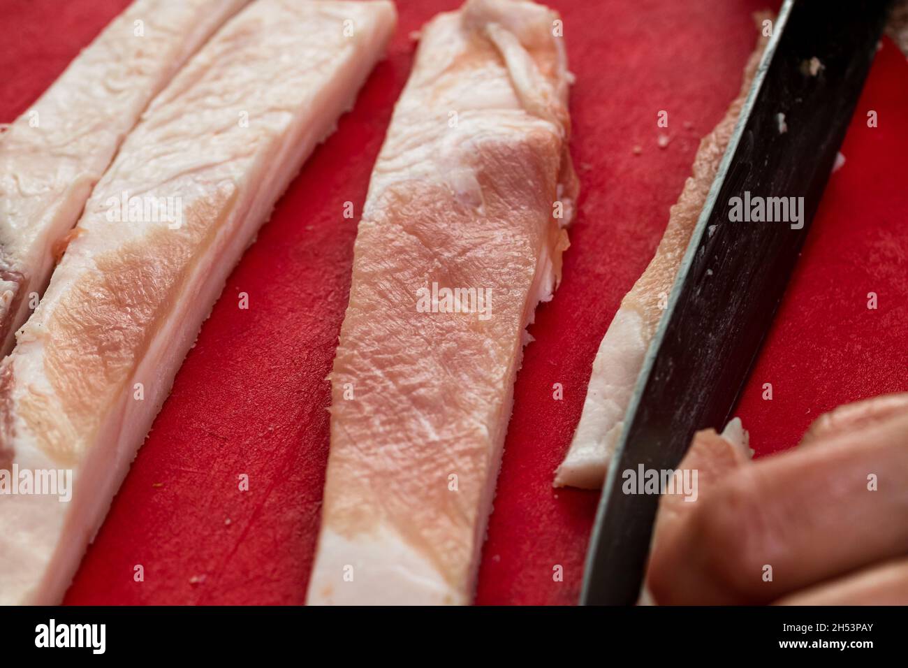 Butcher cutting little pieces of fat pork meat Stock Photo - Alamy
