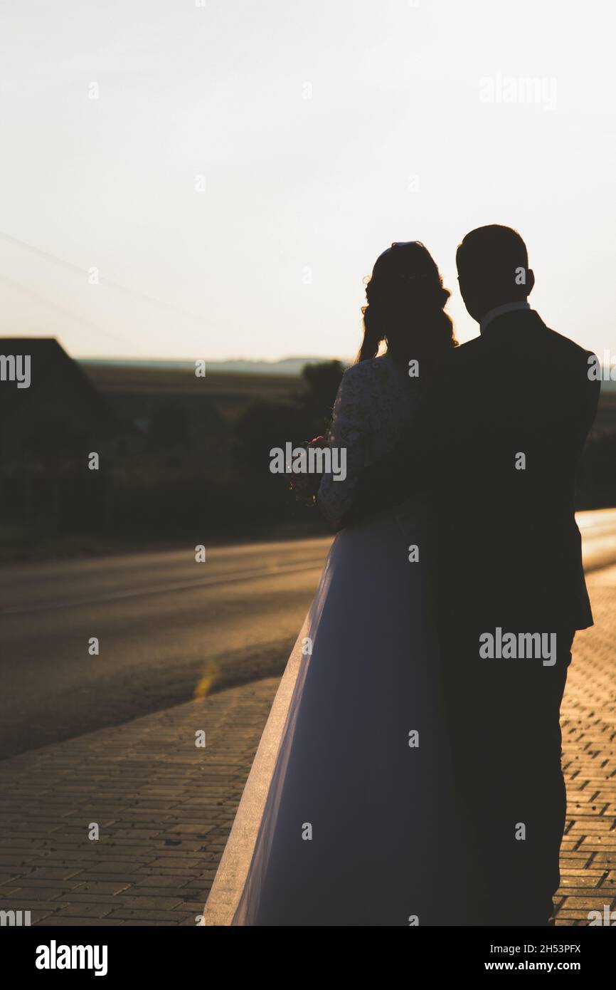 Back view of a newly married couple on the street posing for a ...