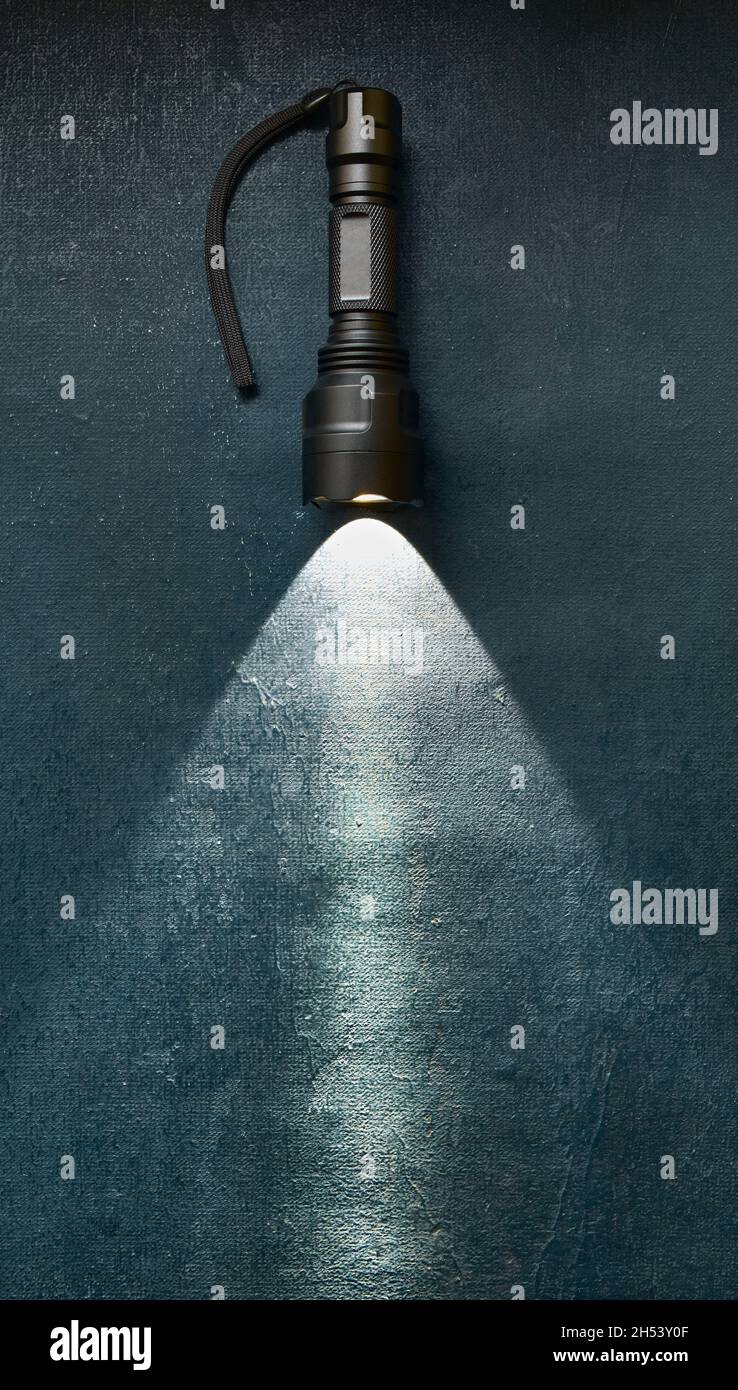 Tactical flashlight shines with bright beam on grunge dark blue ...