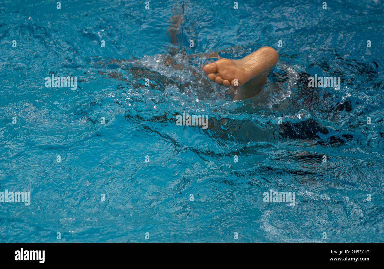 Body submerged in pool water with only right foot out above surface ...