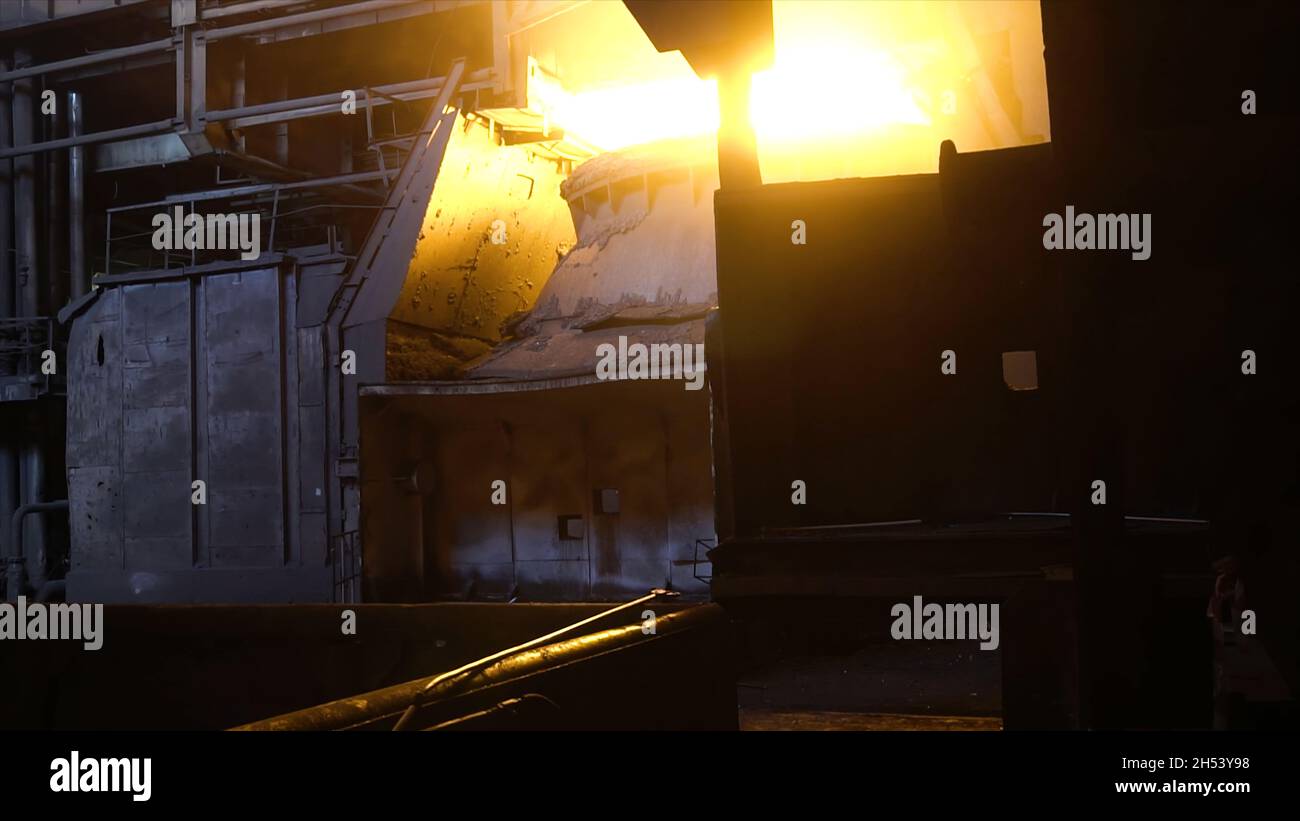 Interior view of steel mill with huge ladle of burning metal alloy ...
