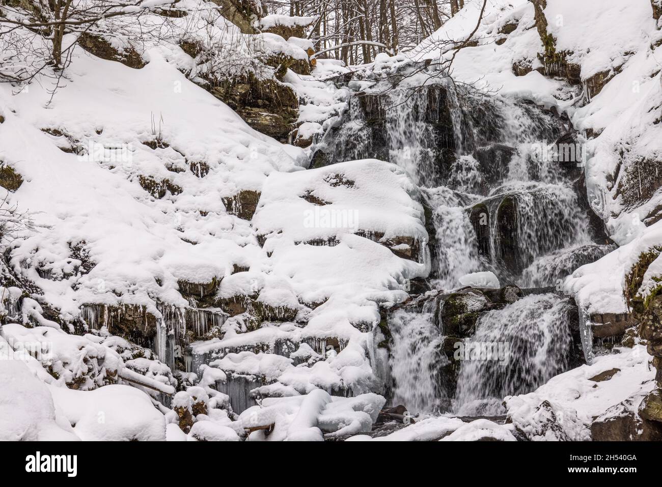 Small mountain waterfall of icy water flow among wet stones covered ...