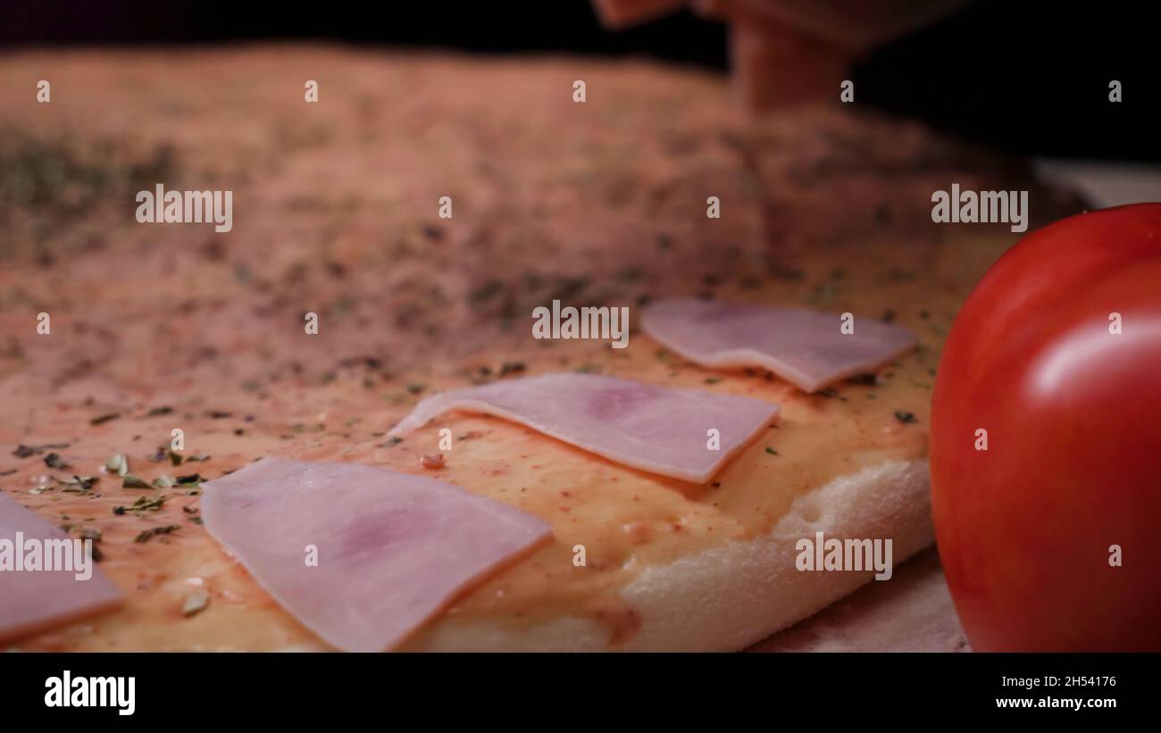 Chef prepares a pizza, putting ingredients on the dough. Frame ...