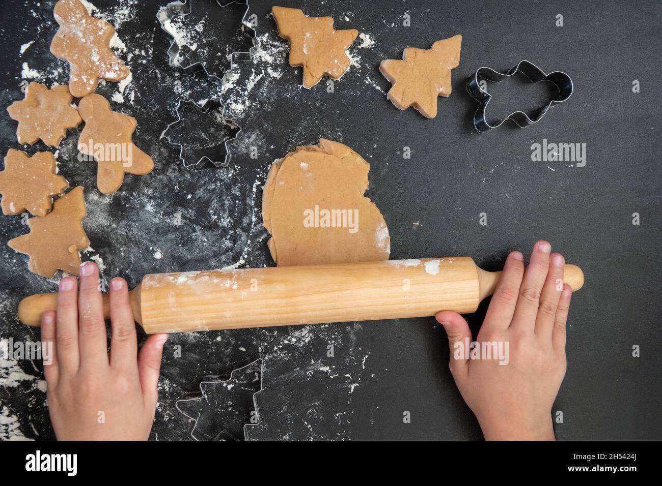 Children's hands make New Year's gingerbread cookies on a wooden table ...