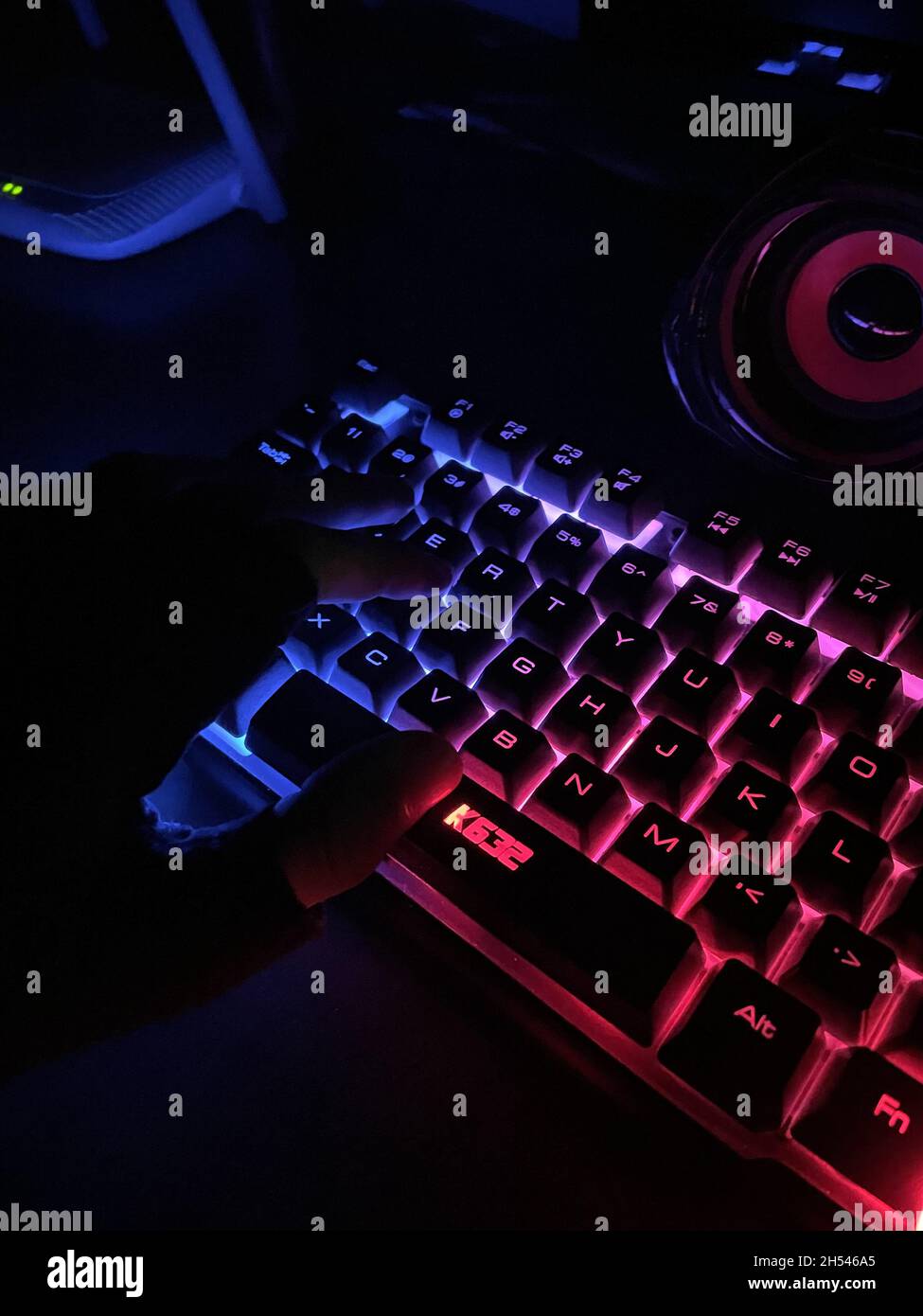 Vertical shot of a hand typing on an illuminated with colorful lights ...