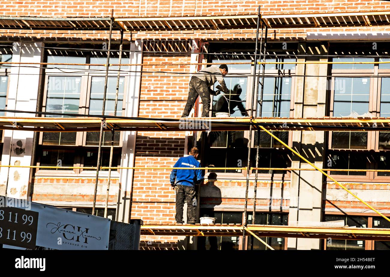 Builders carry out finishing works of the facade on the scaffolding ...