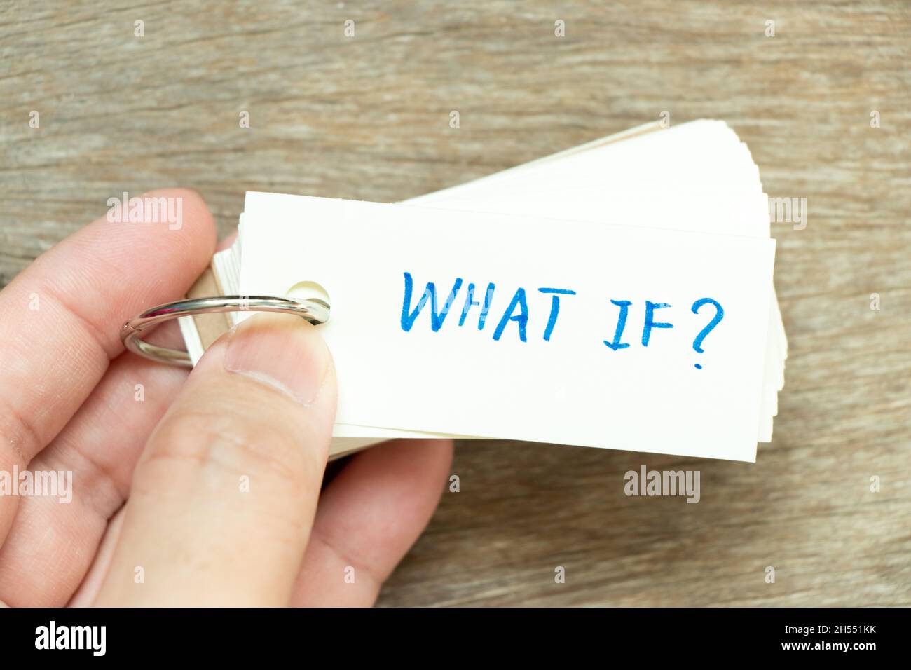 Man hold the flash card with handwriting word what if on wood ...