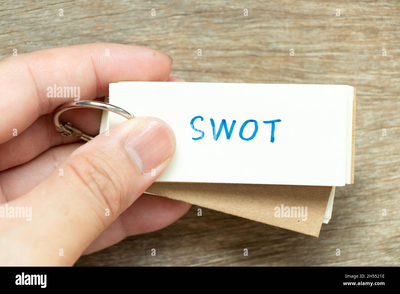 Man hold the flash card with handwriting word SWOT (abbreviation of ...