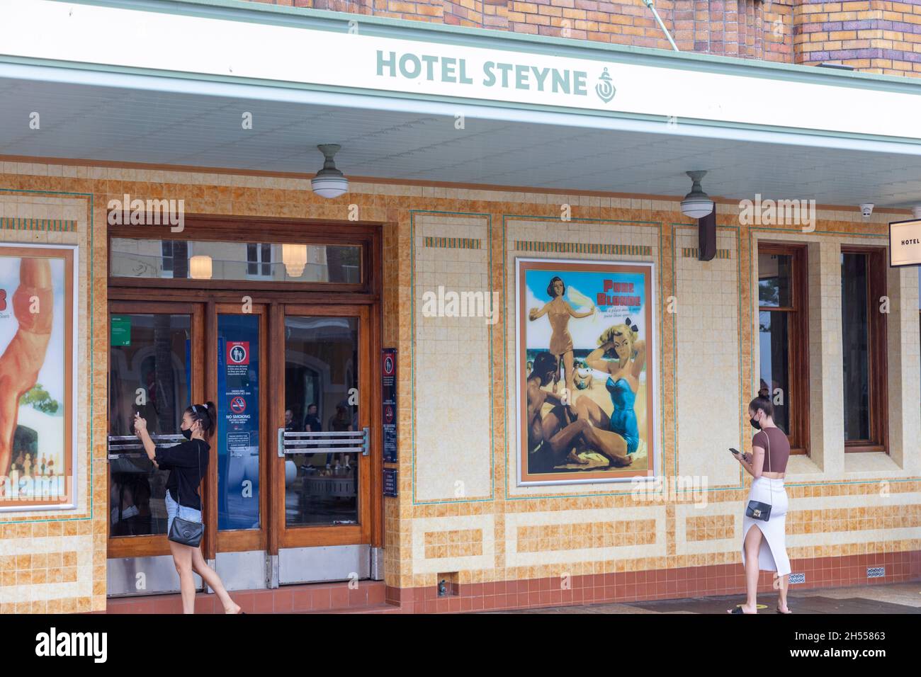 Covid 19 young woman in Manly Beach Sydney lifts her phone to scan the ...