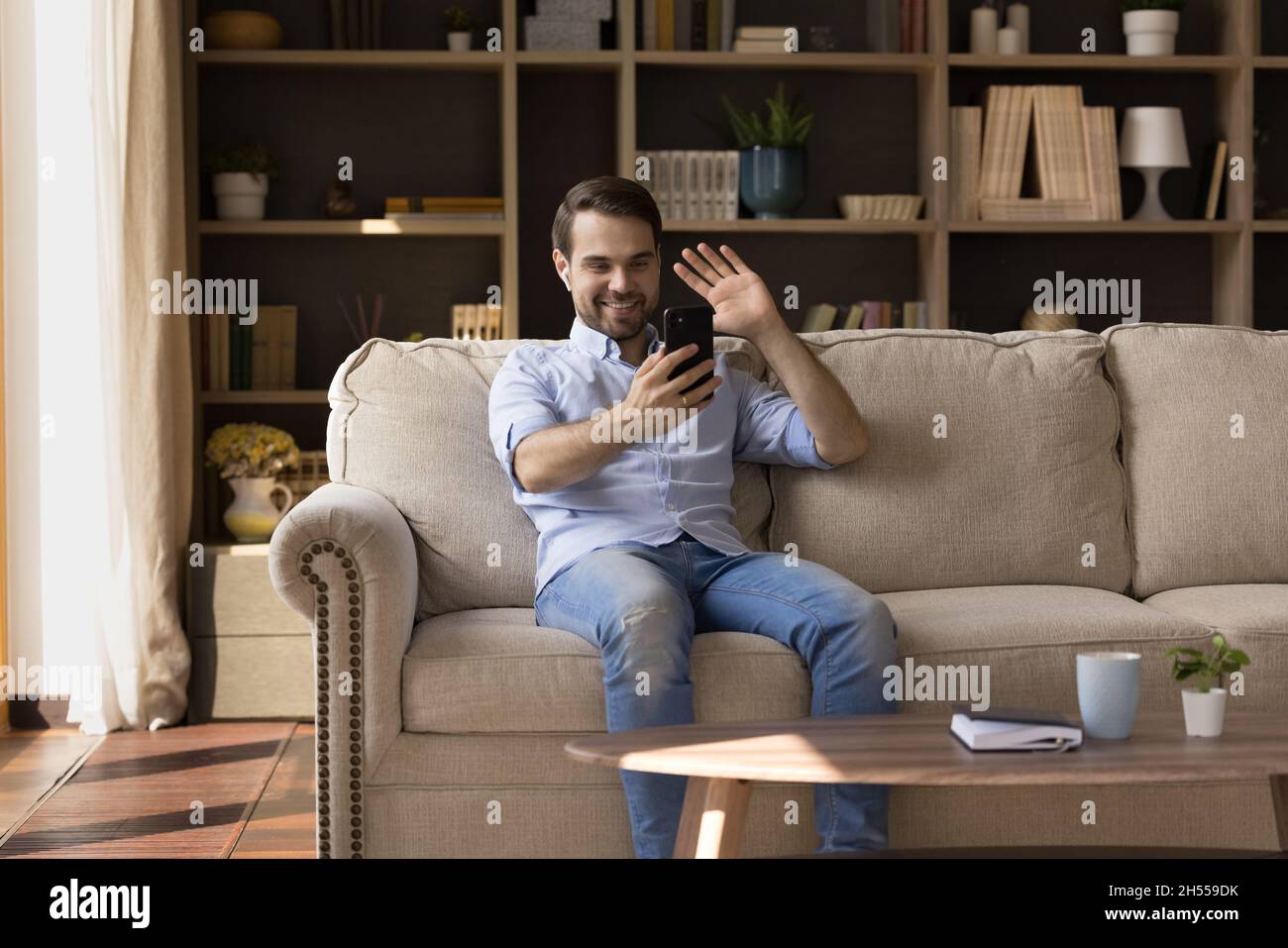Happy young relaxed man holding video call Stock Photo - Alamy