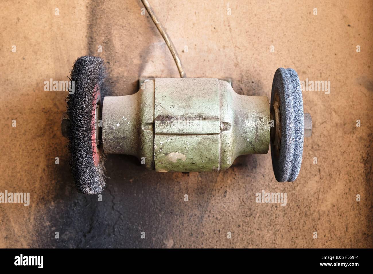 Worn old electric bench grinding machine or grinder mounted on the wall ...