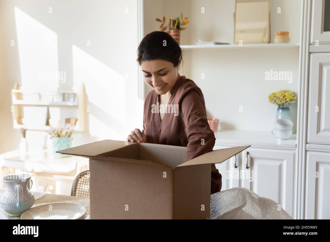 Young Indian woman unpack parcel box with ordered crockery Stock Photo ...
