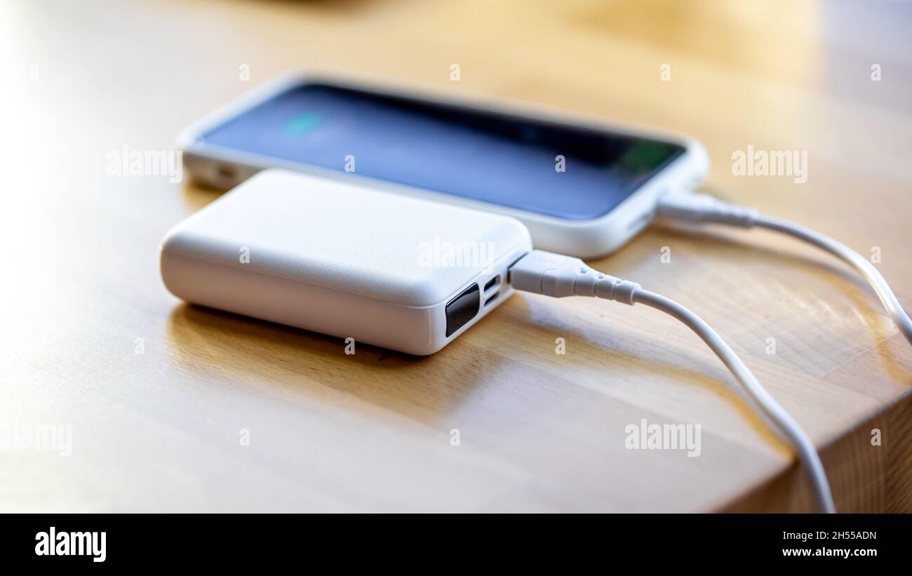 A smartphone is charged from a small white power bank Stock Photo - Alamy