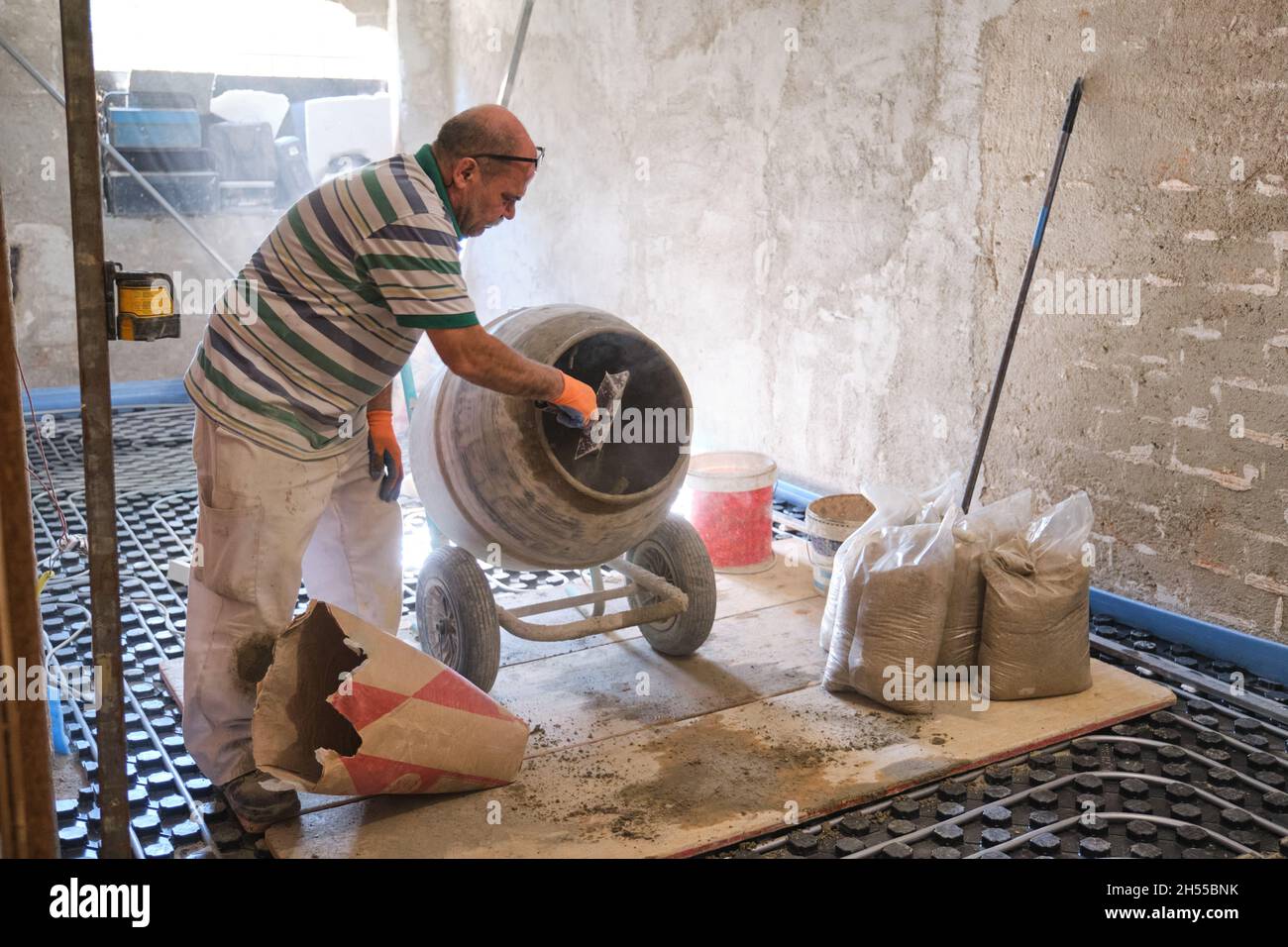 Construction worker loading lime mortar into the concrete mixer Stock ...