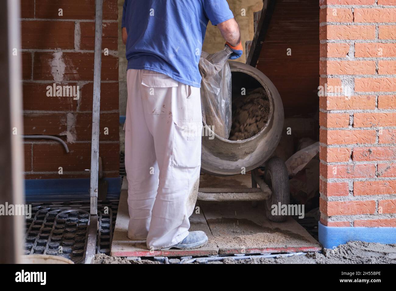 Construction worker loading a sandbag into the concrete mixer Stock ...