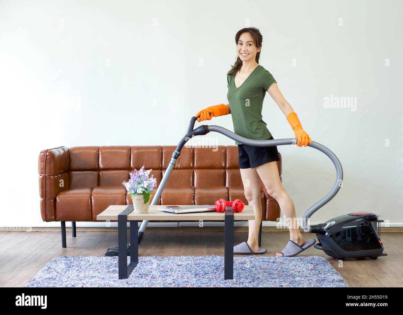 Asian Housewife Wearing Rubber Gloves While Cleaning The Living Room