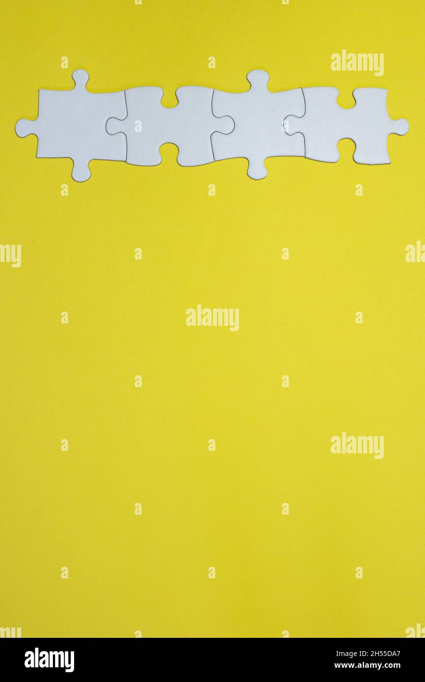 A 4 white jigsaw tiles joined together. vertical image with yellow ...
