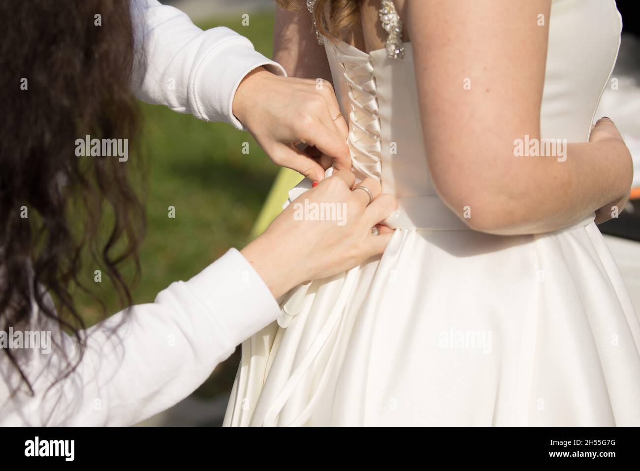A closeup of a female helping a bride to wear a wedding dress Stock ...