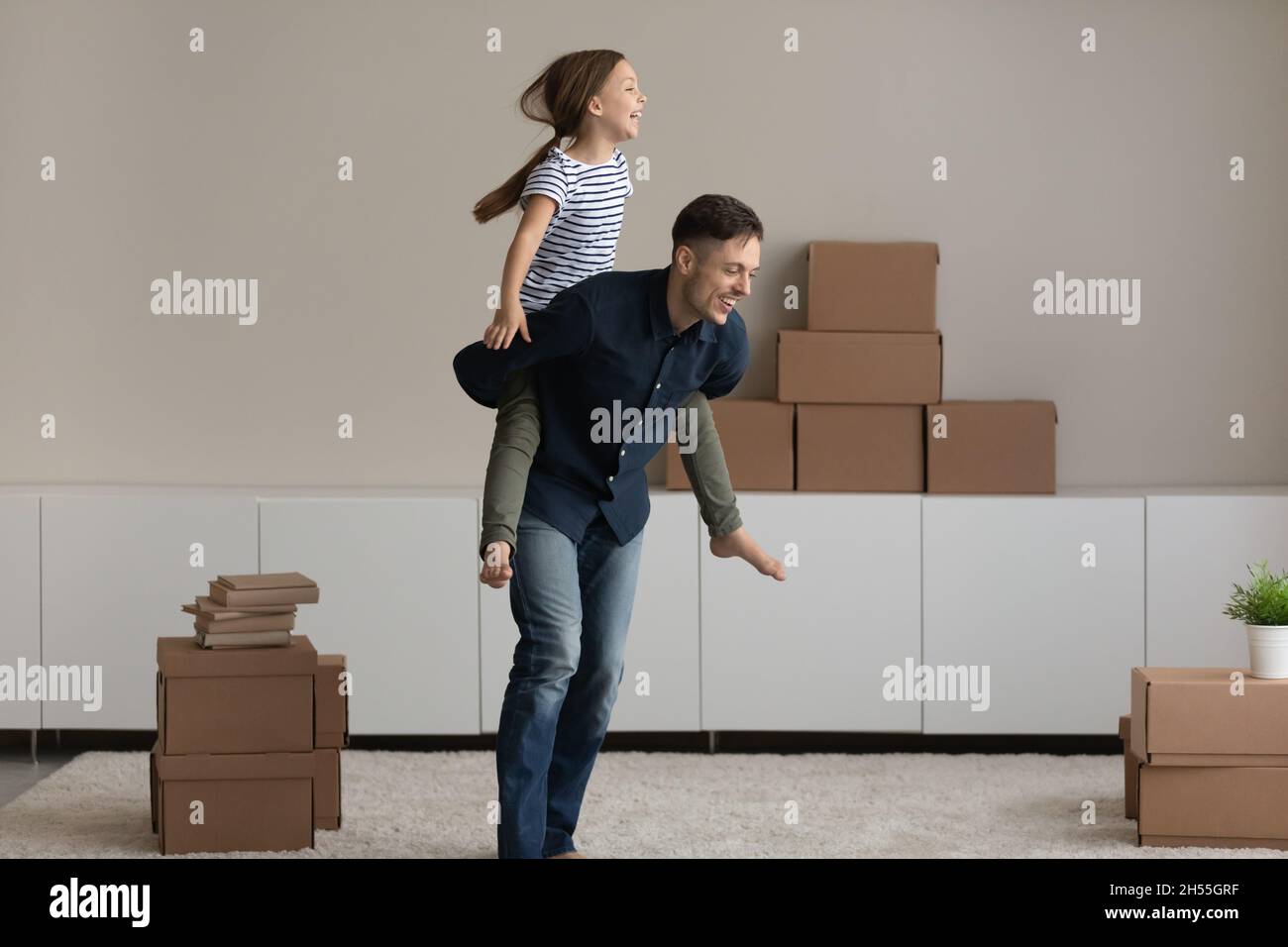 Excited father piggy backing daughter, rejoicing relocation in new home ...