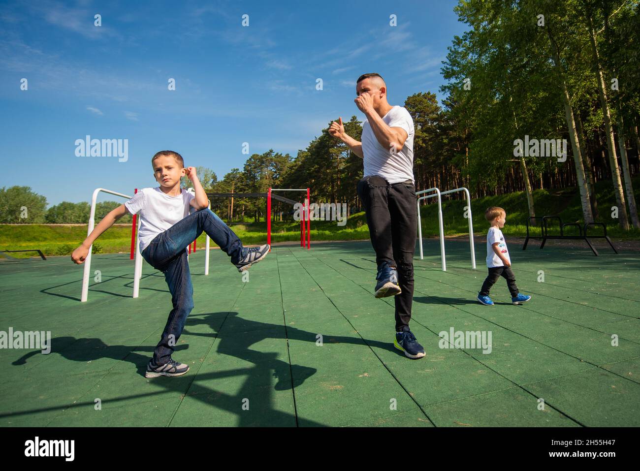 Caucasian man and two boys doing exercises outdoors. Father and sons ...