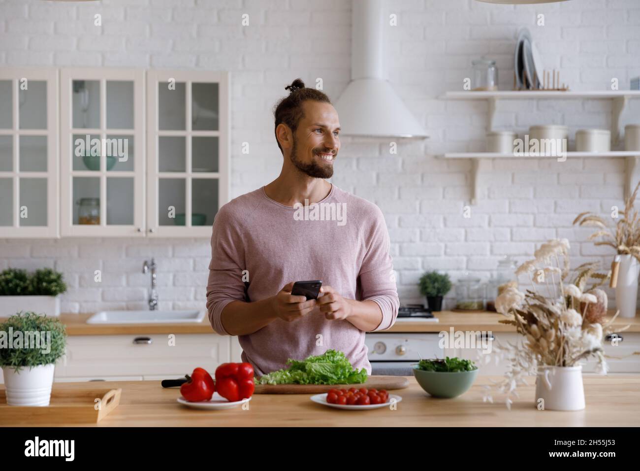 Distracted from cooking food happy young man using smartphone Stock ...