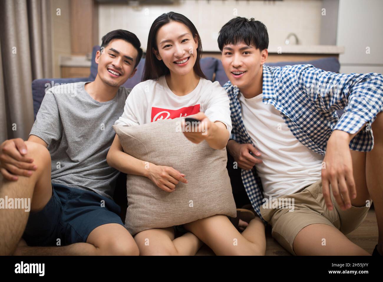 Happy young people watching TV at home Stock Photo - Alamy