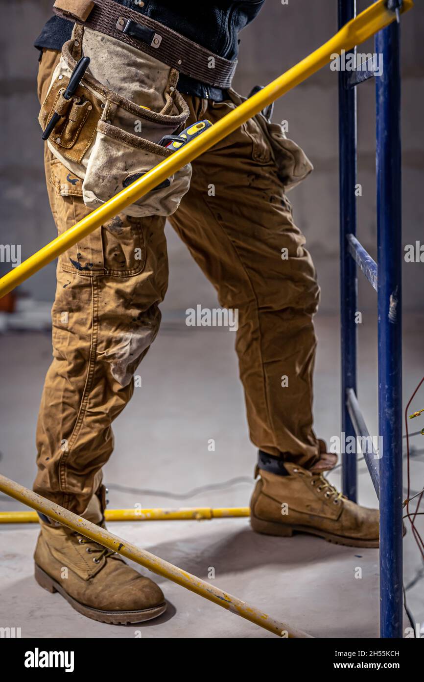 A male electrician works in a switchboard with an electrical connecting ...