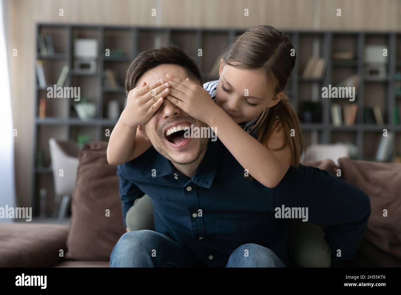 Daughter making surprise for excited father, covering eyes with hands ...