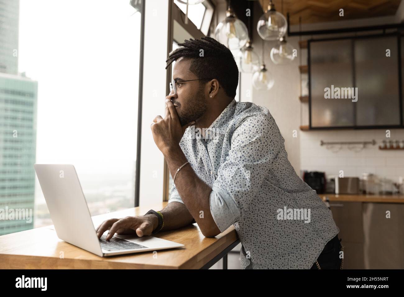 Distracted from computer work dreamy african man looking in distance ...