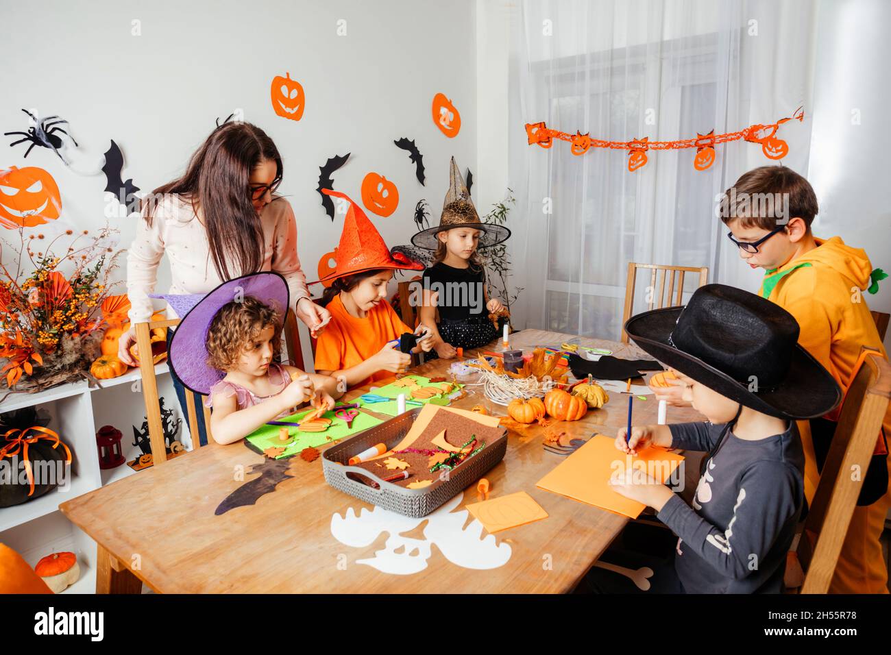 Teacher helping creative children to make paper bookmarks Stock Photo ...