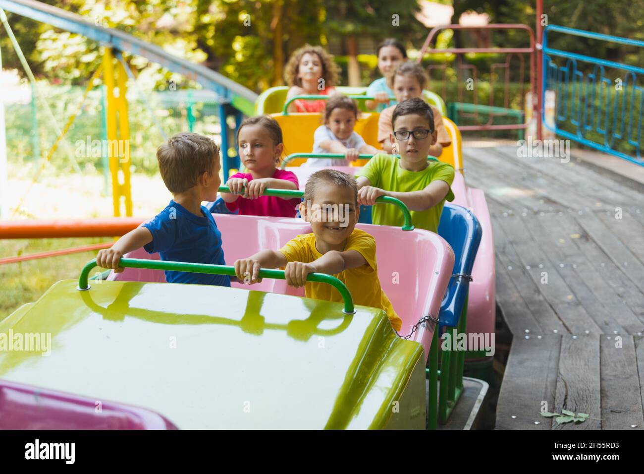 The happy kids on a roller coaster in the amusement park Stock Photo ...