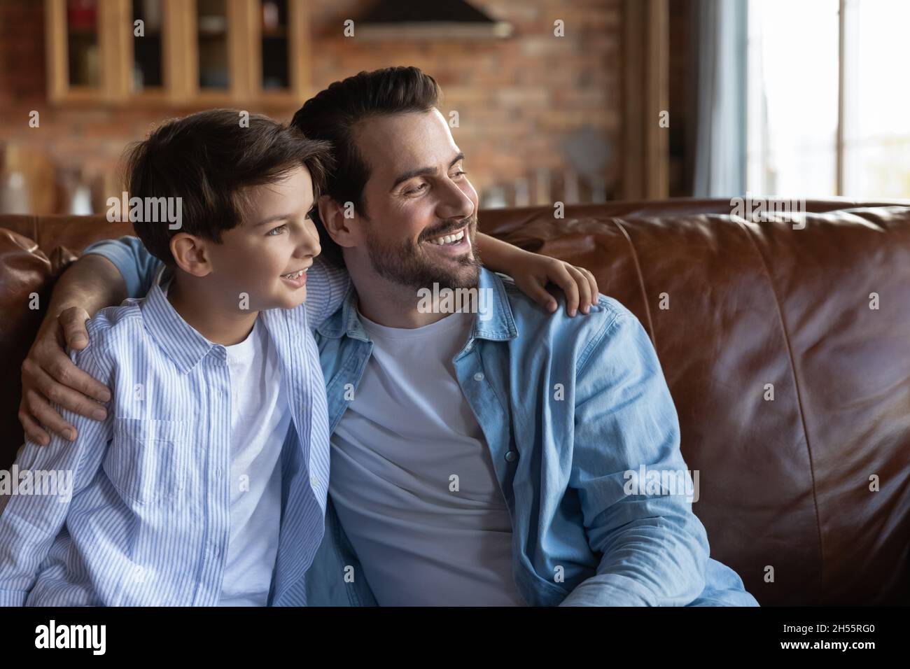 Smiling young man father hugging beloved child son dreaming together ...