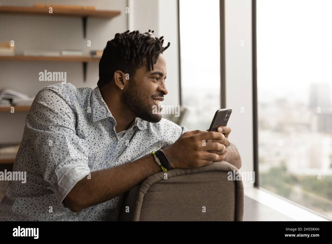 Smiling mixed race young man with cellphone feeling dreamy Stock Photo - Alamy