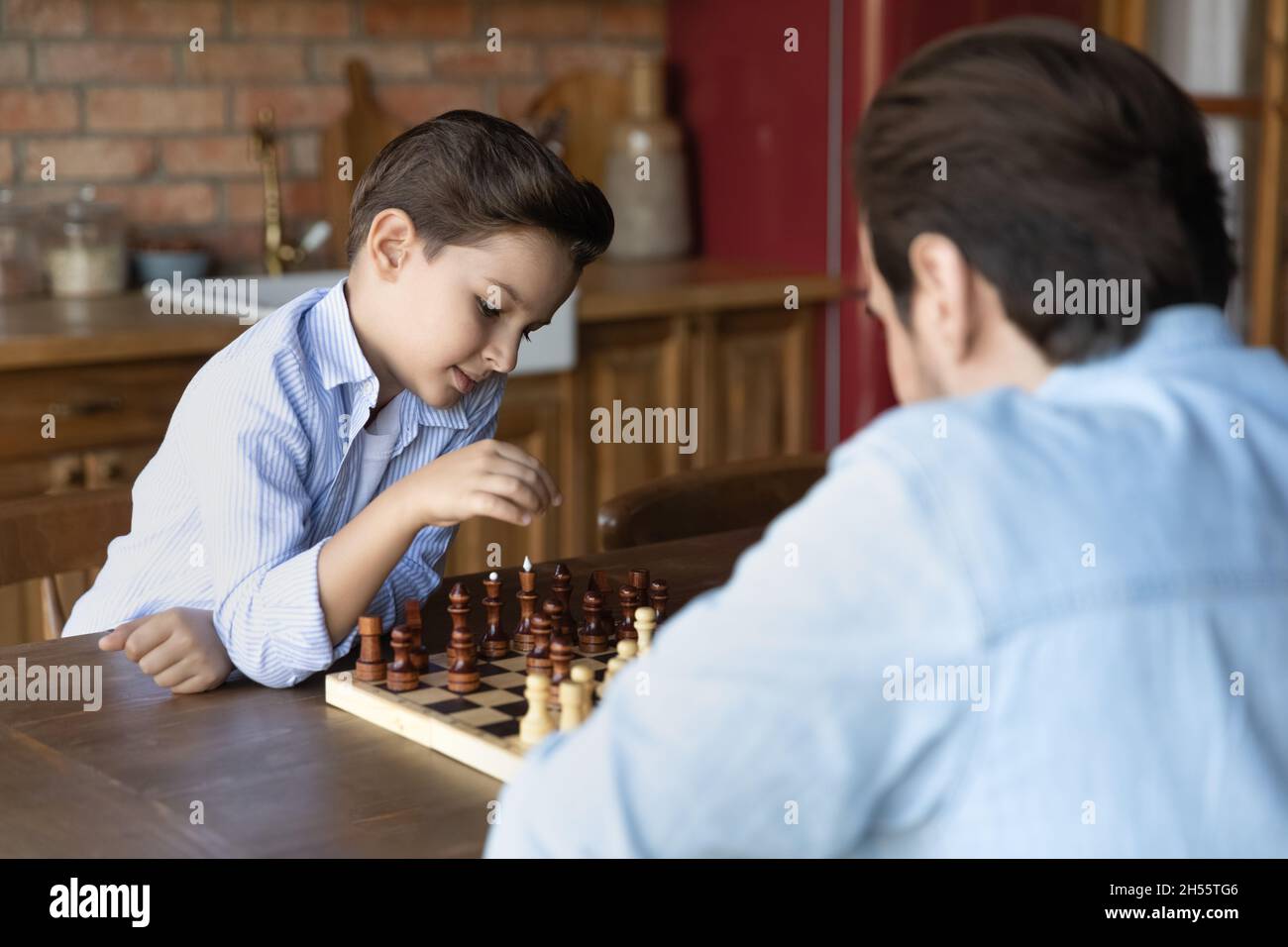 Clever junior school age boy playing chess with dad Stock Photo - Alamy