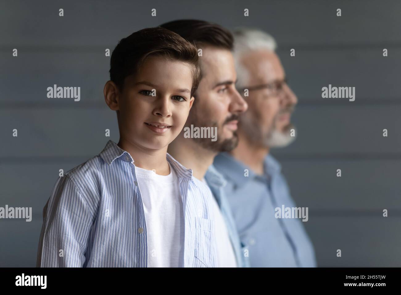 Three diverse men grandfather father little boy stand in row Stock ...