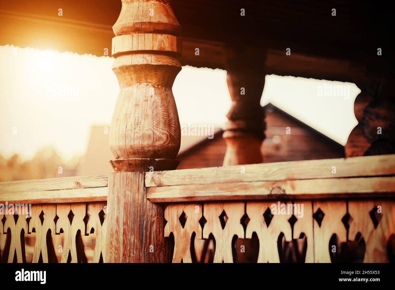 The veranda of the rustic wooden hut is decorated with carved railings ...