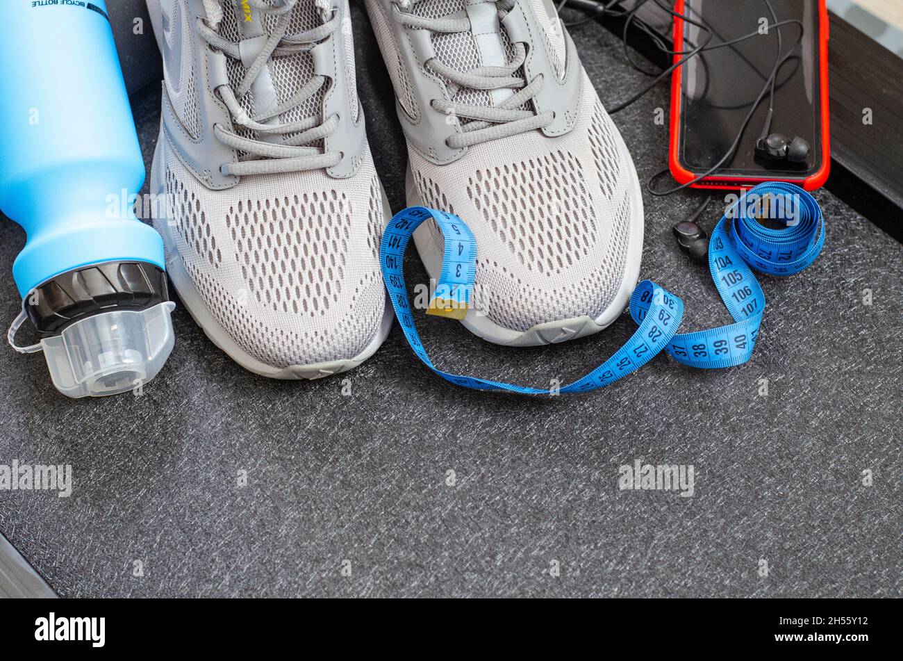 Running track with sneakers and bottle of water on black background ...
