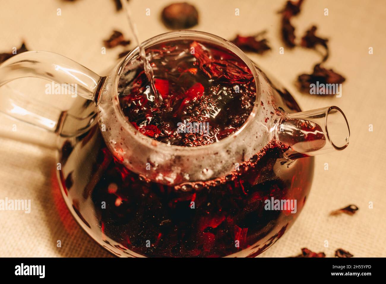 Pouring hot boiling water into the glass teapot. Making pink coloured ...