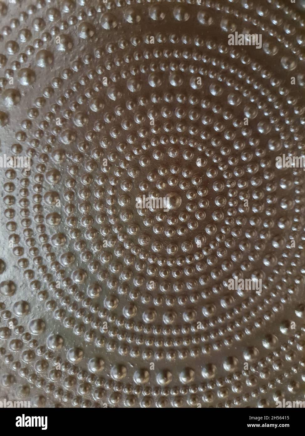 Metal plate with balls of various sizes, forming circles, in golden ...